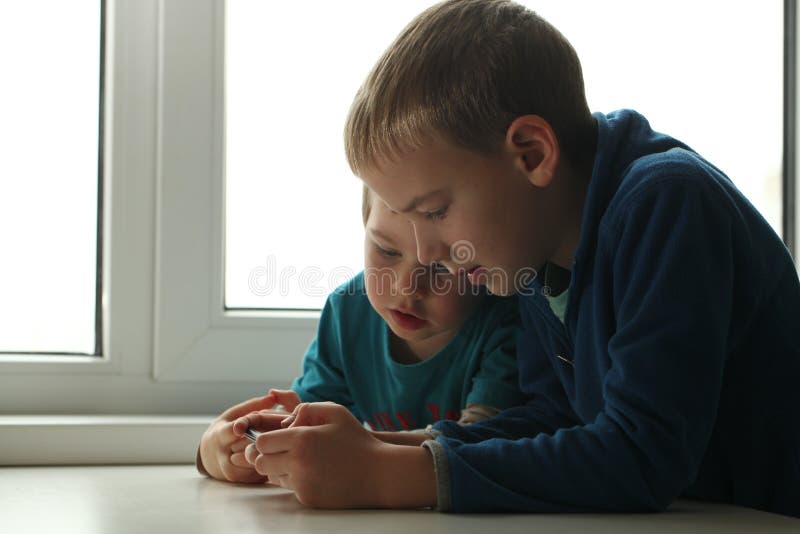 Game Addiction in Children Two Children Playing with a Smartphone while ...