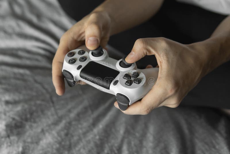 Gamer in White Tshirt Holding a Gamepad in Hands and Sitting on a Couch ...