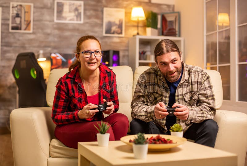 Gamers Couple Playing Video Games on the TV with Wireless Controllers ...