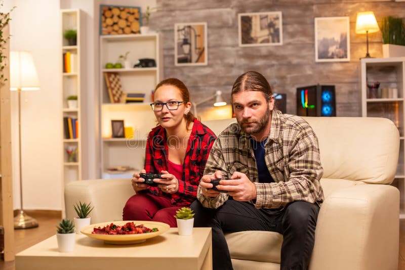 Gamers Couple Playing Video Games on the TV with Wireless Controllers ...
