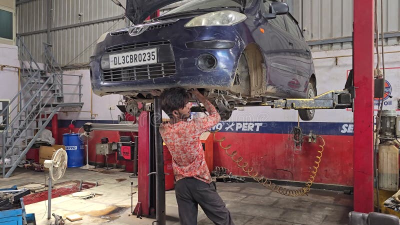 16-6-24 in the Garage, a Mechanic Stands Under a Suspended Car, Fixing ...