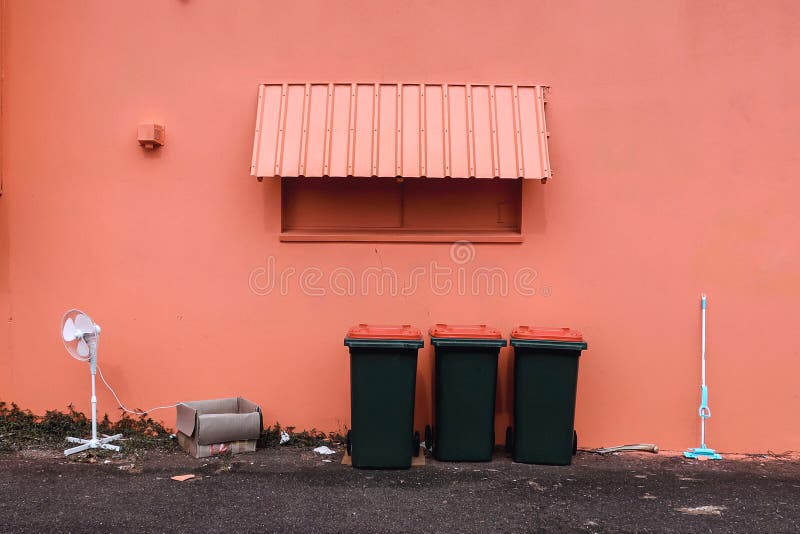 Garbage Bins and Discarded Items in Front of Orange Wall Stock Image ...