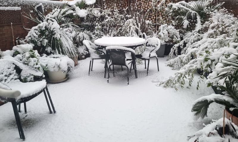 Snow Blankets a Garden Patio with a Table and Chairs during a Winter ...