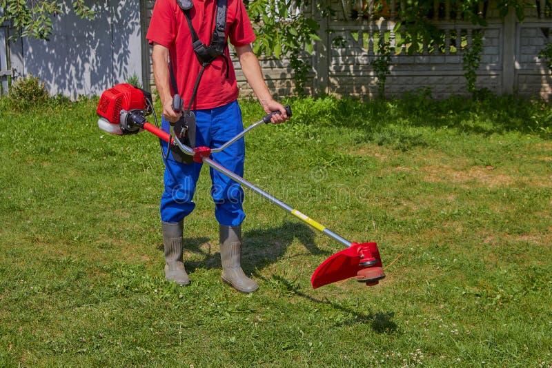 A Gardener with a Brush Cutter in the Yard,work on Mowing the Grass ...