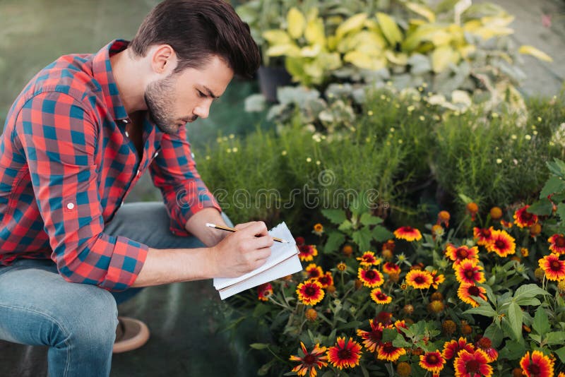 Gardener Making Notes in Notebook while Checking Plants in Garden Stock ...