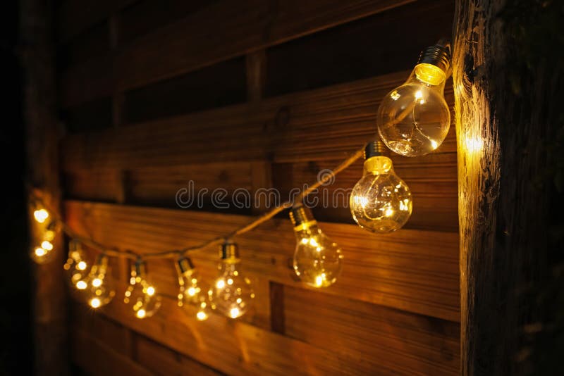 Garland of Lamp Bulbs Hanging on Wooden Wall. String Lights Stock Image ...