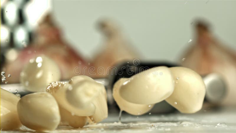 Garlic Falls on a Light Table with Splashes. Filmed on a High-speed ...