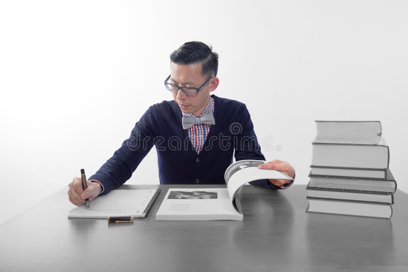 Geek Chic: Man Writing on Notepad, with Open Book and Stack of Books on ...