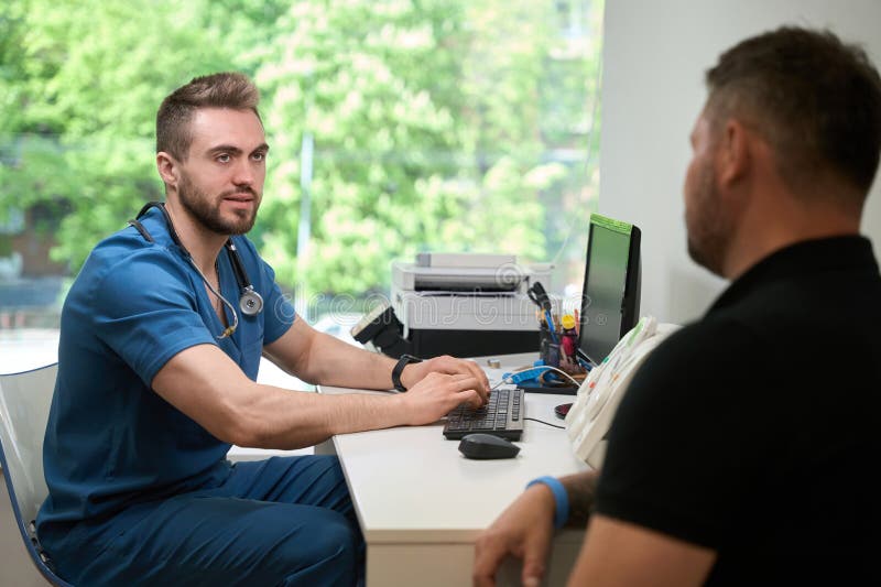 General Practitioner Entering Patient Information into His Desktop ...