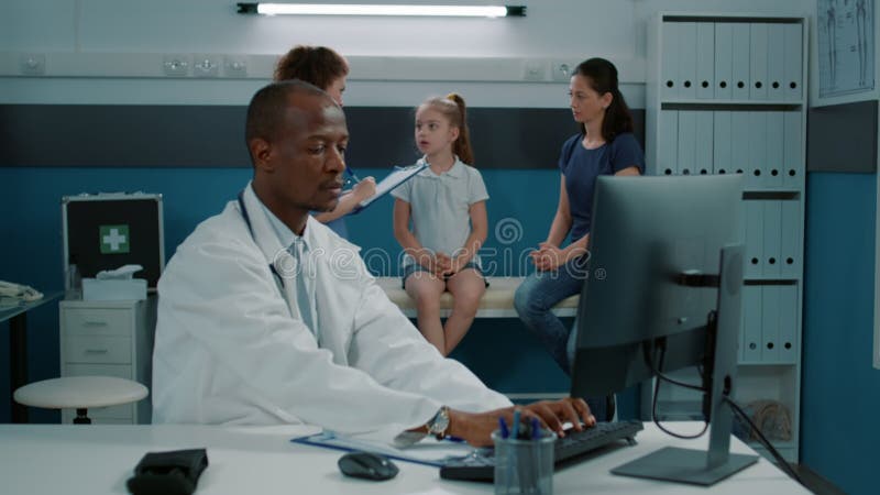 General Practitioner Working on Computer To Help with Treatment Stock ...