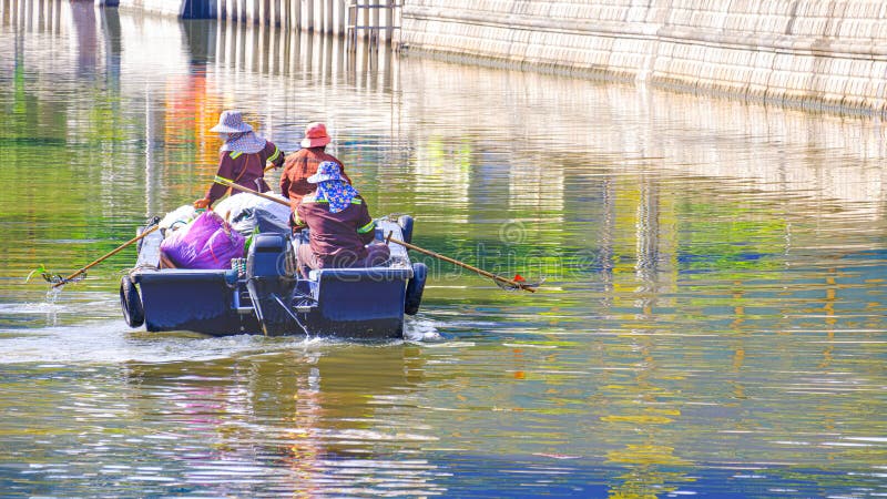 Three Cleaner Workers in a Boat are Cleaning and Collecting Trash in a ...
