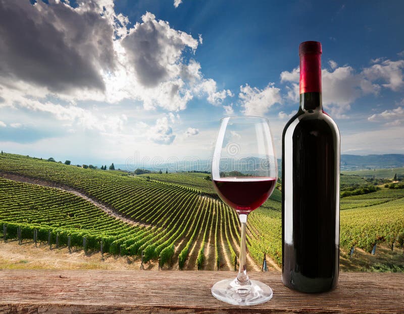 Glass and Bottle of Red Wine Against Vineyard Landscape and Sky with ...