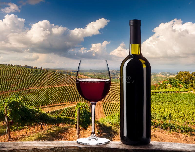 Glass and Bottle of Red Wine Against Vineyard Landscape and Sky with ...