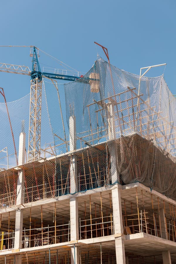Bustling Construction Site with a Towering Crane and Protective Netting ...