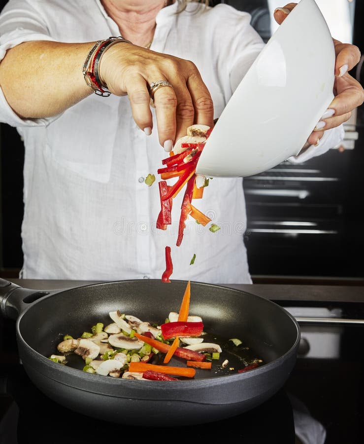 A Chef Tosses Ingredients into a Pan on an Electric Stove Stock Image ...