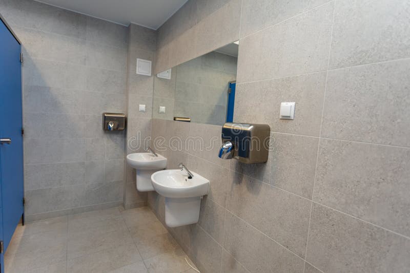 Modern Restroom Featuring Dual Basins, Attractive Hand Dryers, and ...