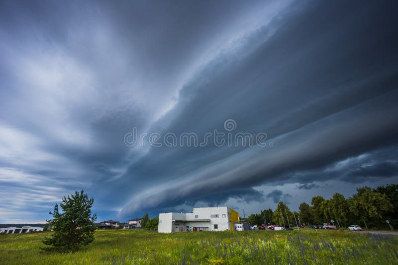 Dramatic Storm Clouds Over Rural House and Green Field Create Ominous ...