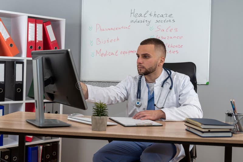 Doctor Man Sitting at the Desk Using Laptop Computer for Webinar ...