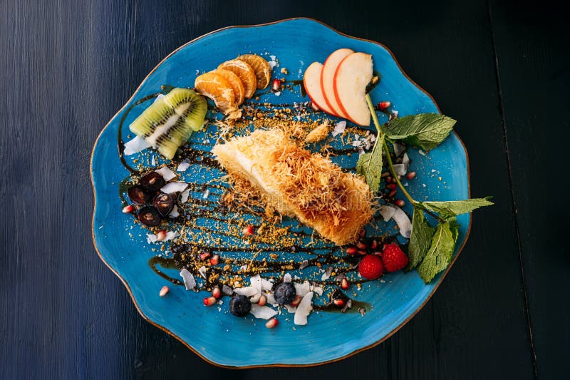 Elegant Dessert with Kunafa and Fresh Fruit Slices on a Blue Plate. a ...