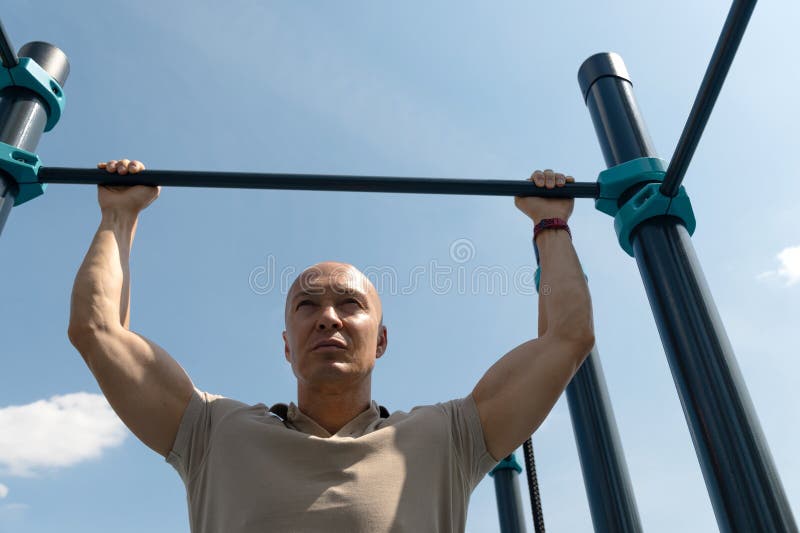 Handsome Man Does Pull-ups on Horizontal Bar at Street on Sports Ground ...