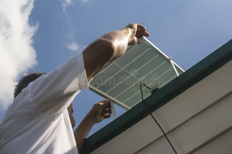 A Man Mounting a Small 50 Watt Polycrystalline Solar Panel on the Eaves ...