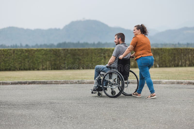 Assistant Helping a Man with Reduced Mobility in a Wheelchair To Move ...