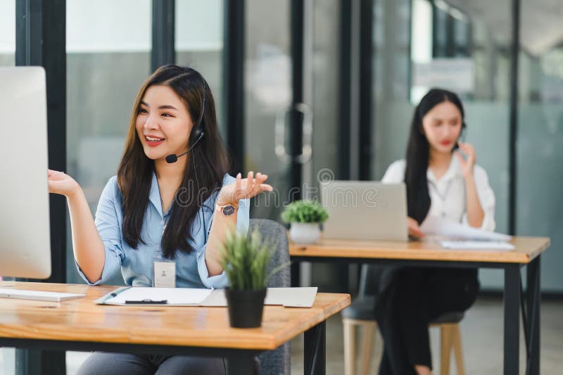 Smiling Call Center Agents Wearing Headsets, Working at Desks with Computers and Documents in a ...