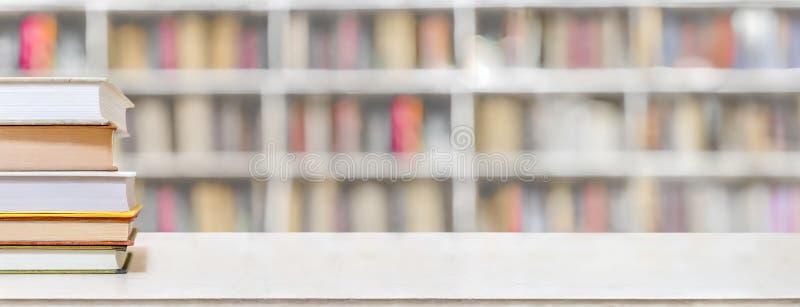 A Stack of Books on a White Table with a Blurred Library Bookshelf ...