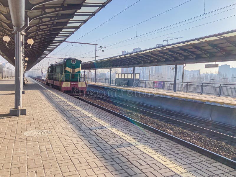 A Static Green Electric Train with Yellow Stripes is at a Red Brick ...