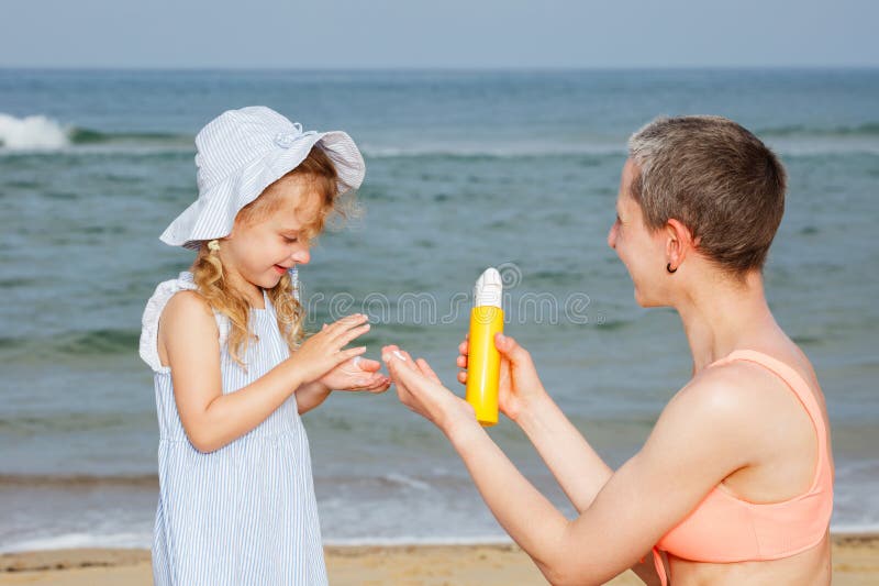 An Adult is Applying Sunscreen Lotion To a Young Girl on Beach Stock ...