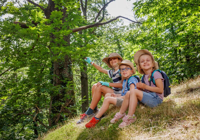 Kids Exploring the Forest, Sitting and Pointing, Wearing Hats Stock ...