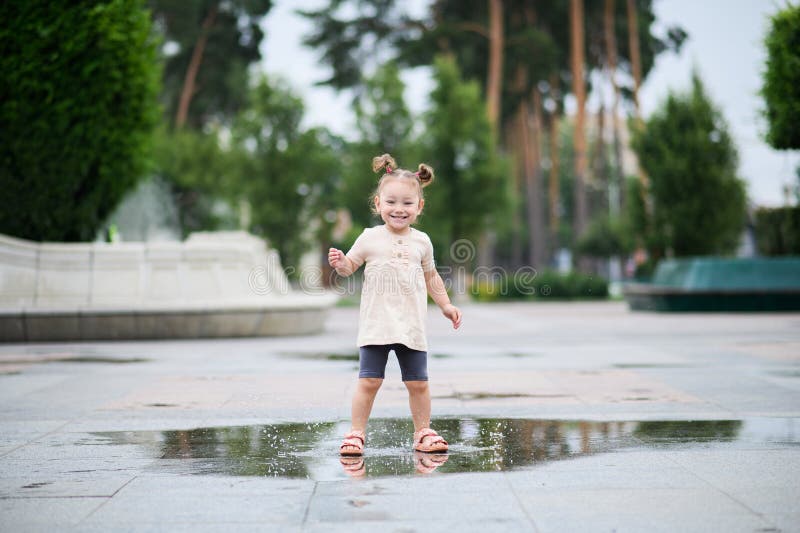 Toddler Girl Jumping through Puddles in Summer Stock Photo - Image of ...