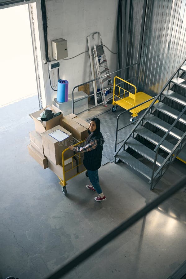 Joyous Loader Posing for Camera while Transporting Goods on Wheeled ...