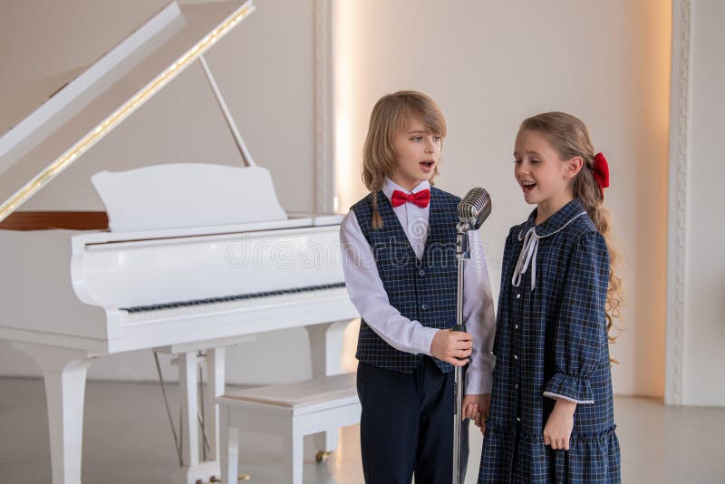 Two Children are Singing in Front of a Piano. Stock Photo - Image of ...