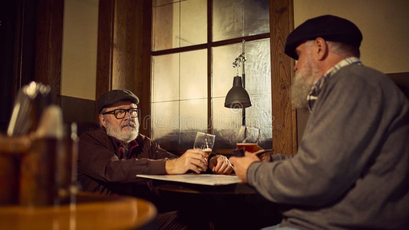 Two Elderly Bearded Men in Retro-style Clothes with Caps, Drinking Beer ...