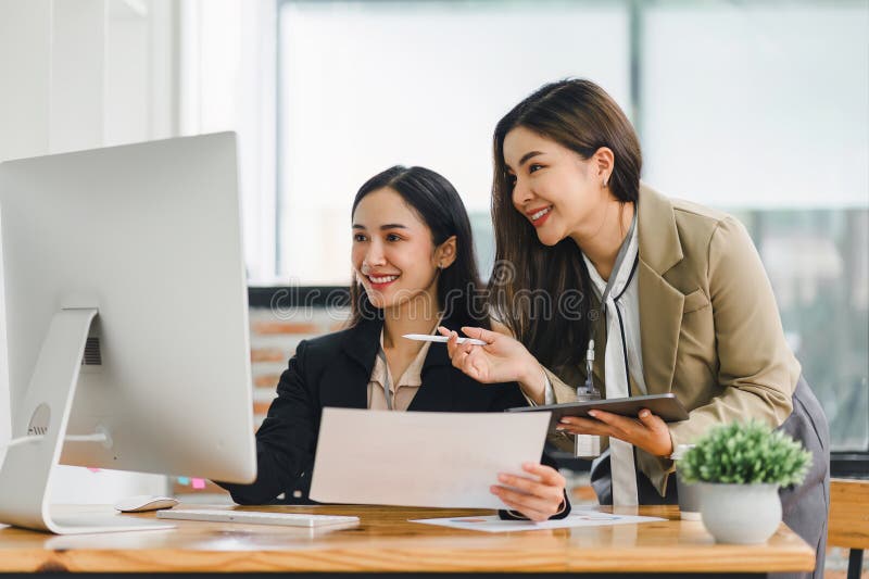 Two Professional Asian Women Collaborating on a Project in Modern ...