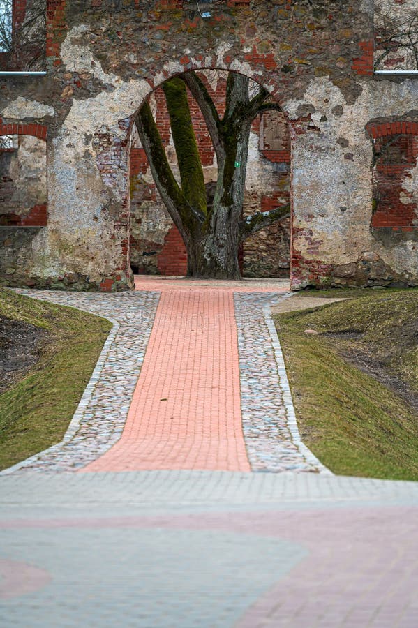A Winding Pathway Passes through an Old Arch, Featuring a Solitary Tree ...