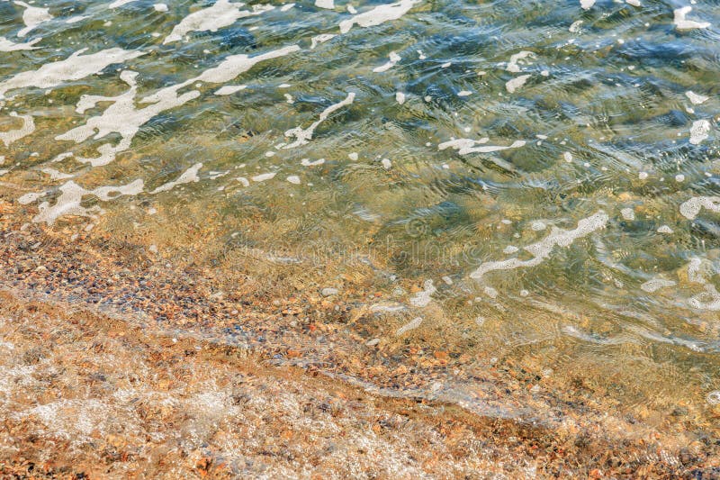 Gentle Waves on Rocky Shoreline with Sunlit Clear Water Stock Image ...