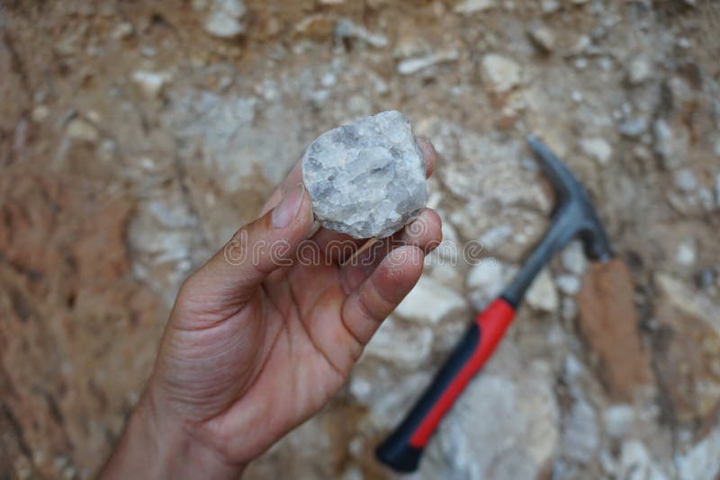 A Geologist`s Hand is Holding a Piece of Quartz Rock on Blur Geological ... A Geologist`s Hand is Holding a Piece of Quartz Rock on Blur Geological ...