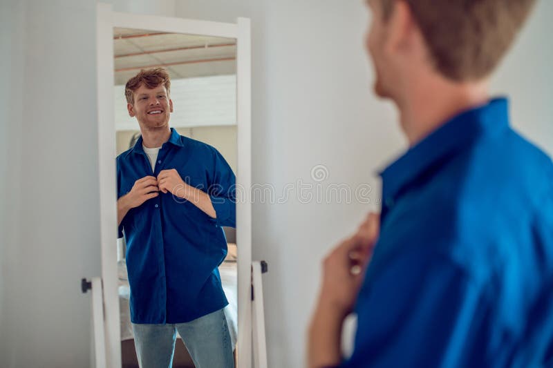 A Confident Young Man Getting Dressed at the Mirror Stock Photo - Image ...