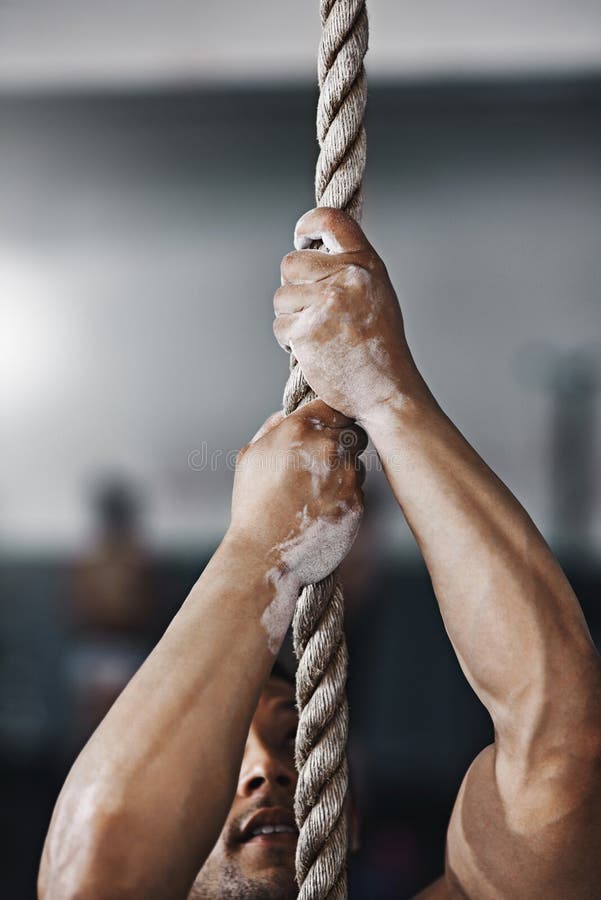 Getting a Good Grip. a Young Man Climbing a Rope at the Gym. Stock ...