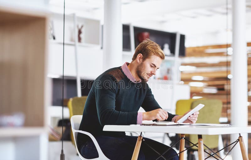 Getting the Job Done. a Young Businssman Using a Digital Tablet at His ...