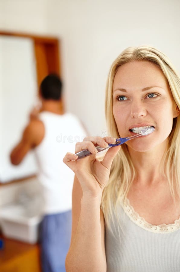 Getting Ready Together. a Woman Brushing Her Teeth while Her Boyfriend ...