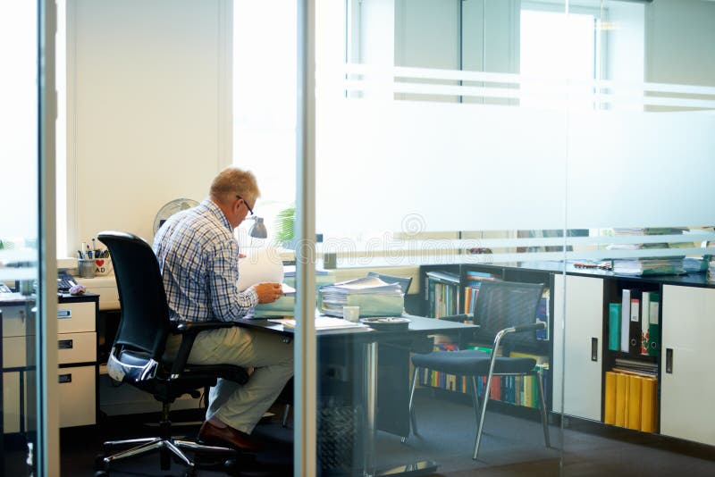 Getting into the Zone at His Desk. a Senior Businessman Working through ...
