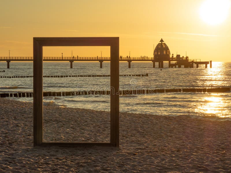 Giant Frame Border on a Sandy Beach with a Pier in the Background ...