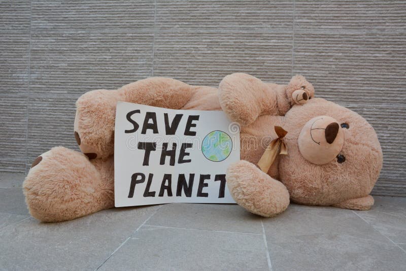 Giant Teddy Bear Lying on the Ground with Save the Planet Poster Stock ...