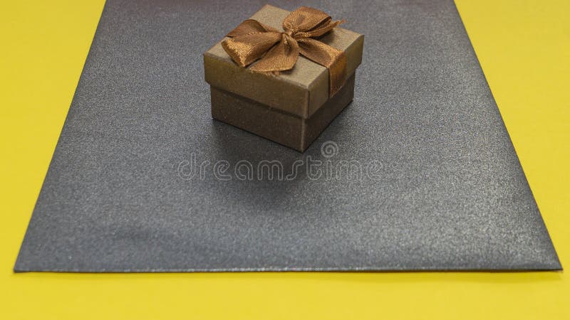 Gift Box in Bronze Color with a Bow and a Black Craft Envelope on a ...