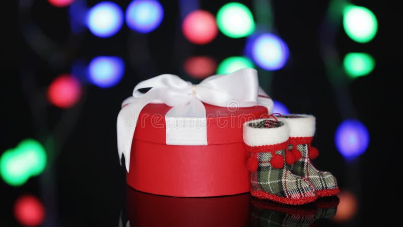 Gift Box and Small Boots Against Glowing Christmas Lights Stock Photo ...