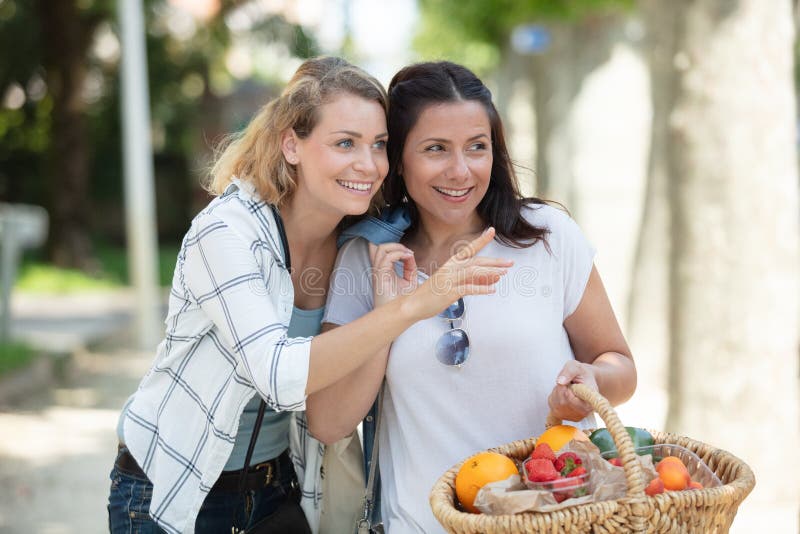 Giggling Women with Basket Vegetables Pointing into Distance Stock ...