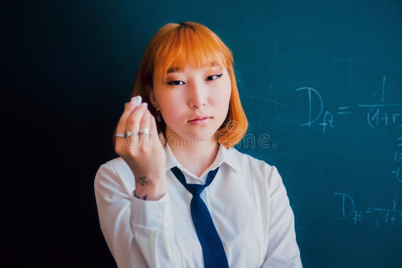 A Ginger Asian Student in Uniform, Sitting at a Desk in an Empty ...